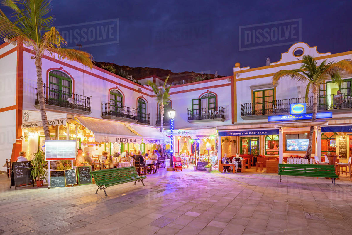 View of cafes and restaurants in Puerto de Mogan and mountainous ...