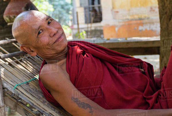 Senior monk resting on reclining chair outside of Shwenandaw Temple ...