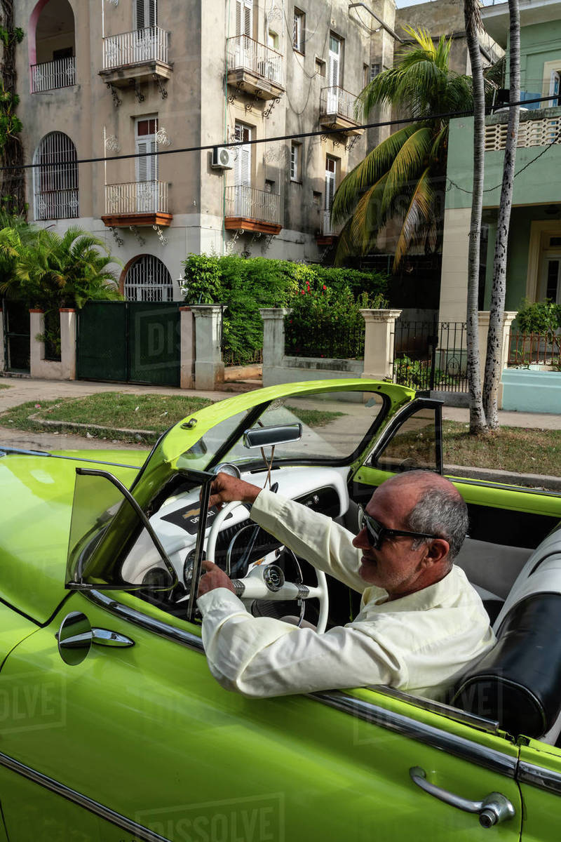 Driver in green open top Chevrolet classic car parked in suburb, Havana ...