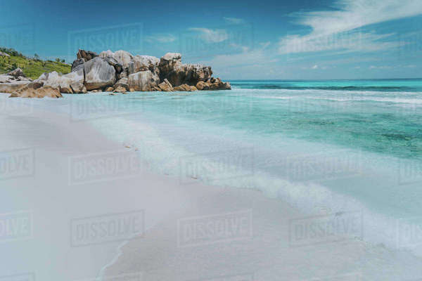 Wave on pristine blue color lagoon with granite rocks on Anse Coco ...