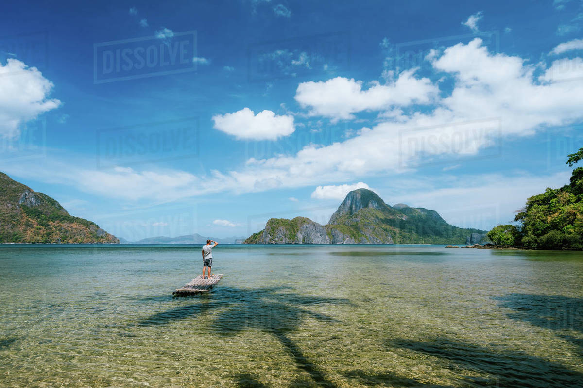 Man on bamboo float in shallow lagoon with panoramic view of shallow ...