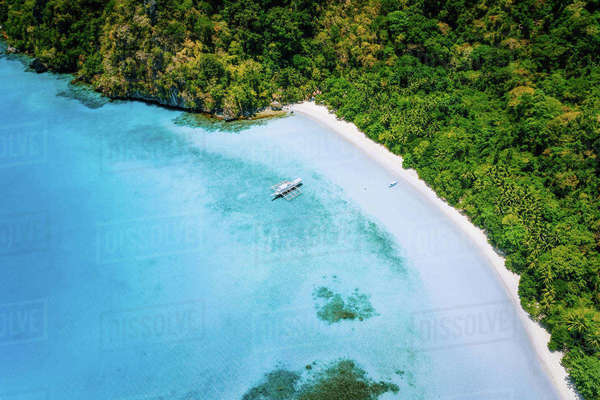 Aerial top down view of boat moored at secluded white sand beach with ...