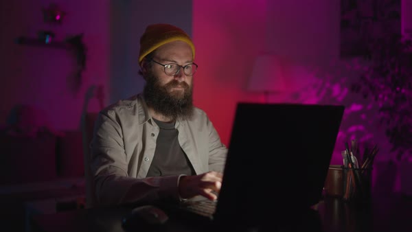 Hacker hacking late at night in neon lights. Inspiration strikes. A ...