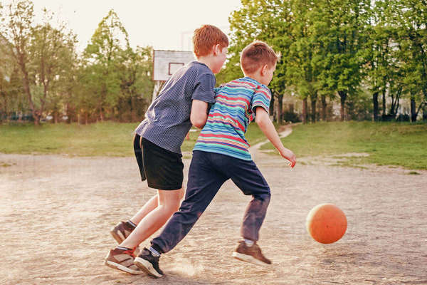 Two young boys chasing a basketball while practicing their game ...