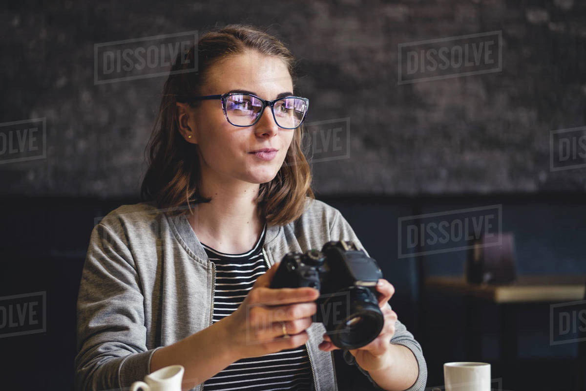 Young woman photographer looking up with a quiet smile as she holds her ...