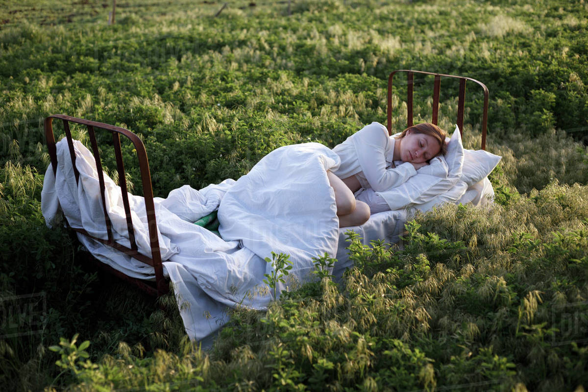 girl sleeping in the bed in a green field. healthy sleep in nature ...