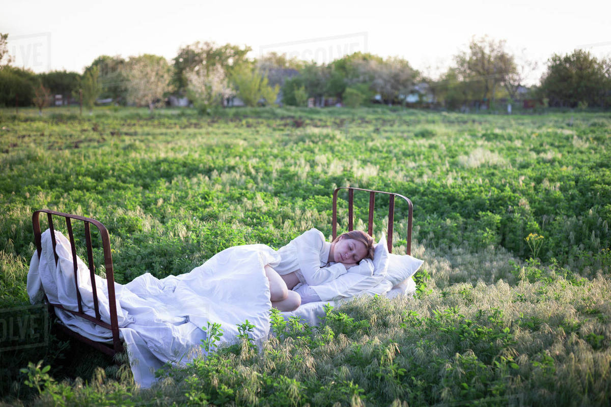 girl sleeping in the bed in a green field. healthy sleep in nature ...