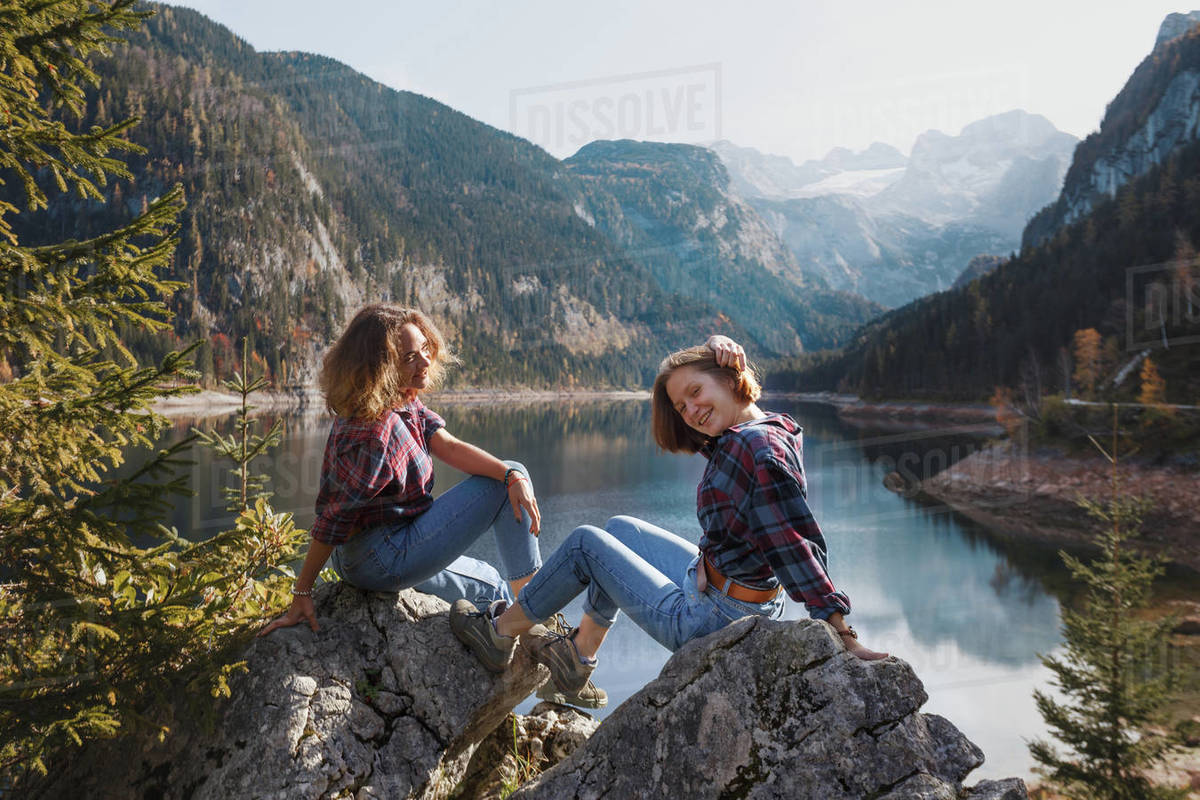 Mountain trip. two happy girls on the background of a mountain lake and ...