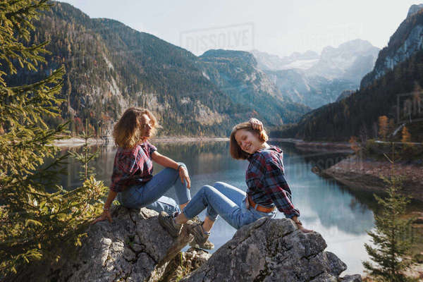 Mountain trip. two happy girls on the background of a mountain lake and ...