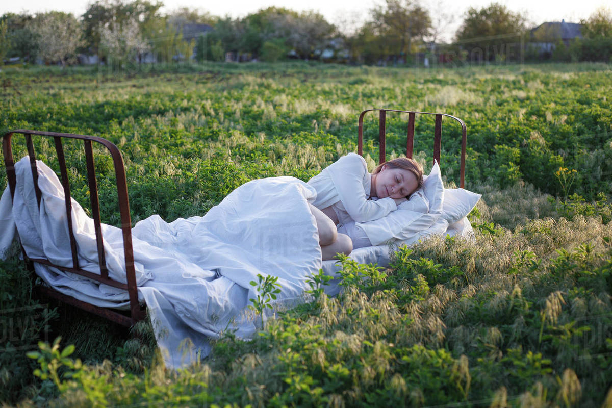 girl sleeping in the bed in a green field. healthy sleep in nature ...