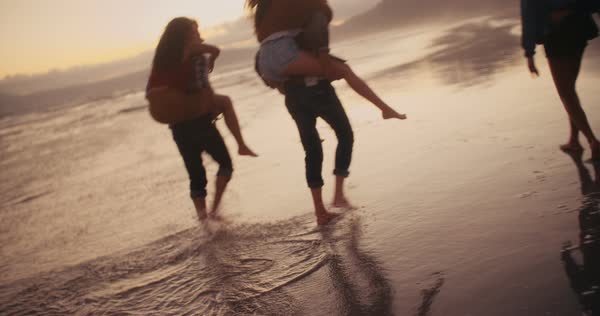 Group of hipster friends having fun on the beach doing piggyback ride ...