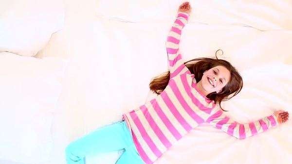 Girl falling backwards onto bed, looking at camera...in slow motion ...