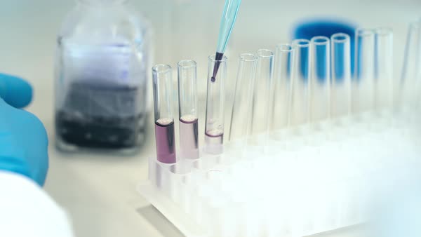 Pipetting a sample into a glass beaker during research in a scientific ...