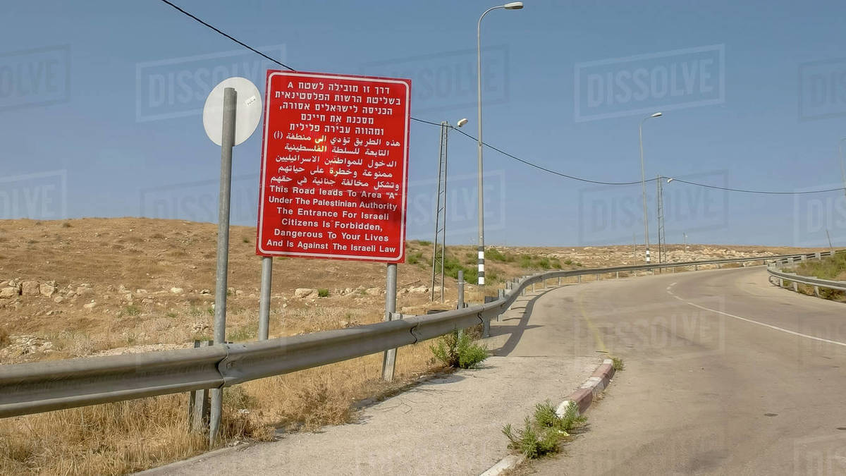 an entry sign by the side of a road to the palestinian territory ...