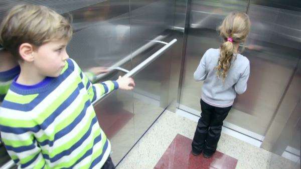 Two kids boy and little girl walk out from elevator when its arrived ...