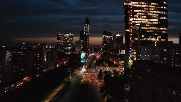 Night city scene, High rise illuminated buildings along wide street ...