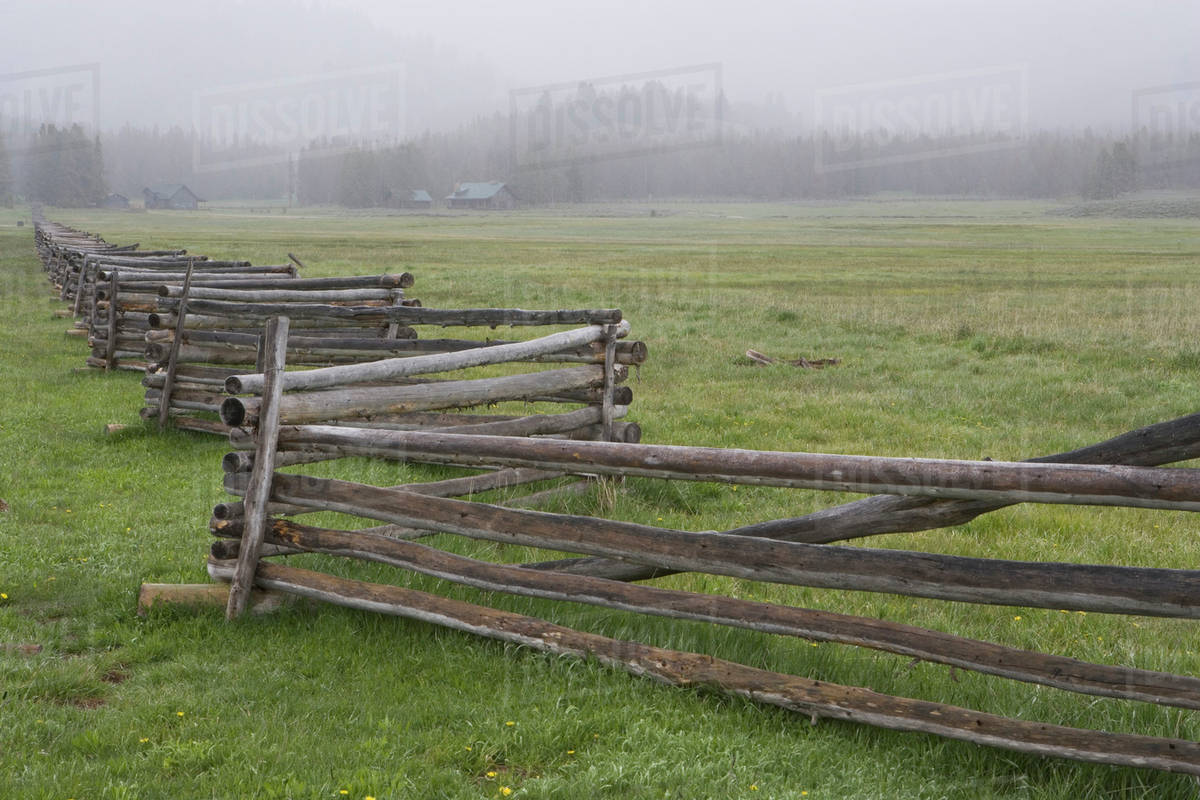 USA, Idaho, Sawtooth Mountains. Split-rail fence divides field in misty ...