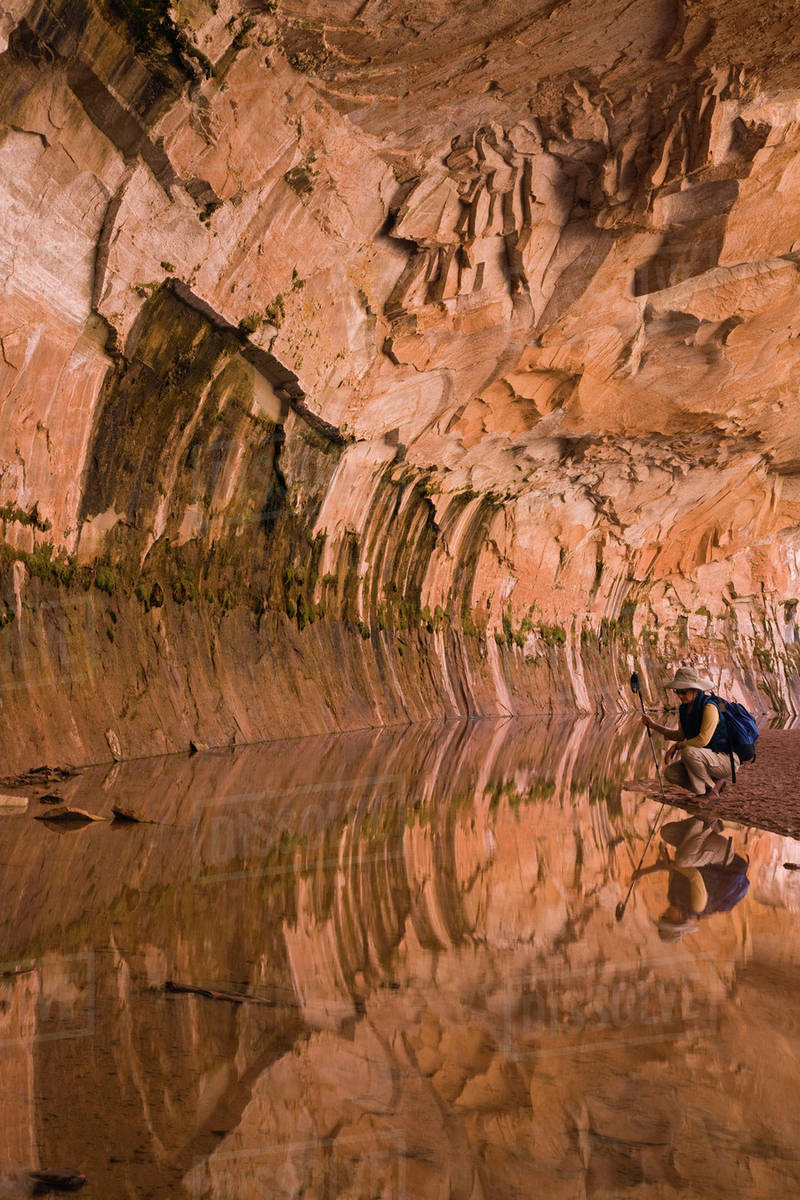 USA, Utah, Green River. Woman hiker kneels next to still water under ...