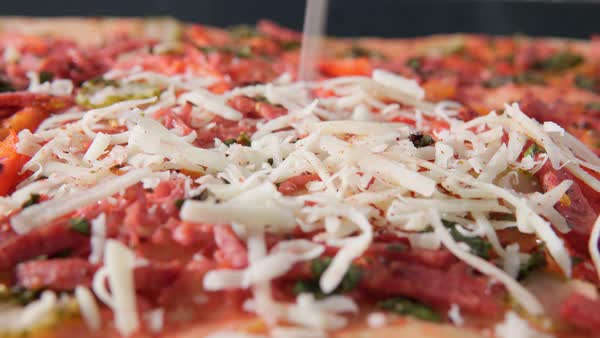 Grating cheese, making pizza. Covering Italian pizza with cheese ...