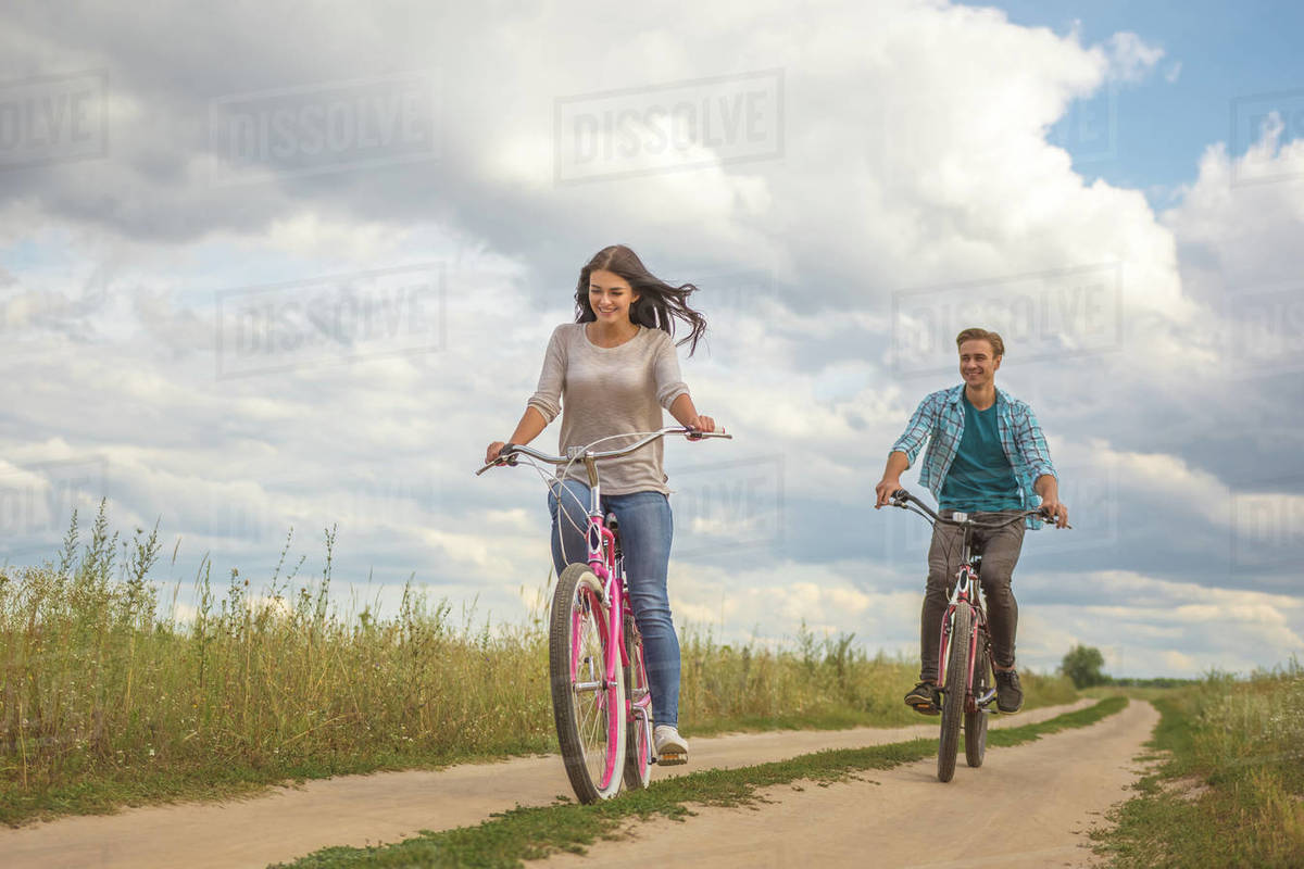 Man and woman riding bikes on a country road - Stock Photo - Dissolve