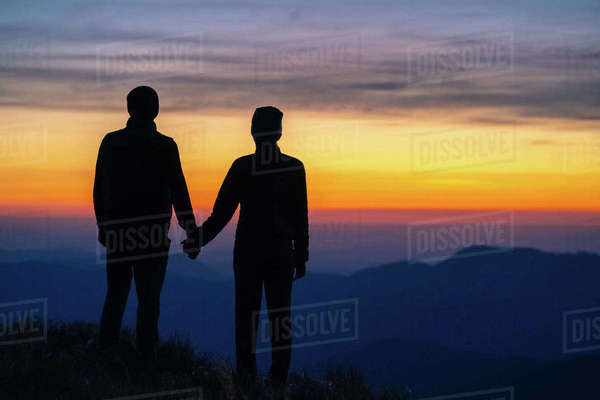 The couple standing on the mountain on a sunrise background - Stock ...