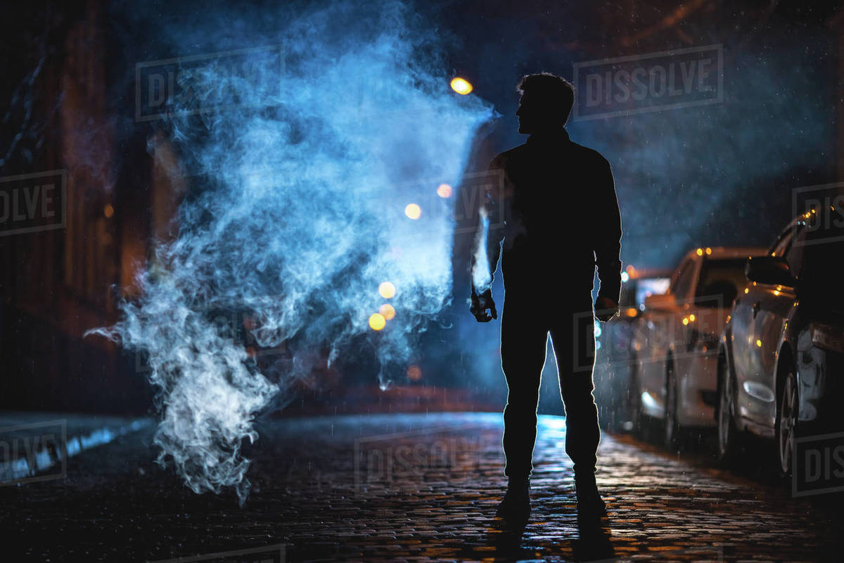 The man smoke on the street. Evening night time. Telephoto lens shot ...