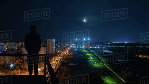 The man standing on the top of building on the night cityscape ...