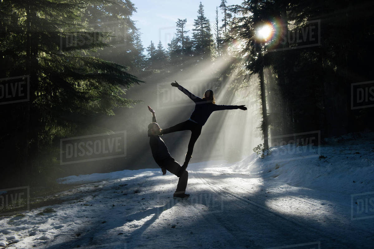 Silhouettes of acrobats in snow covered forest balancing, Frog lake ...