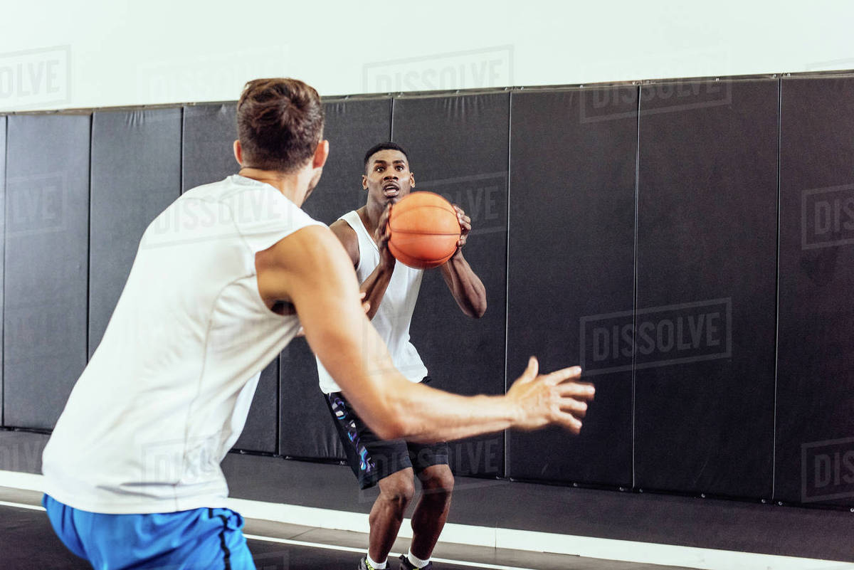 Two male basketball players practicing ball defence and aim on ...