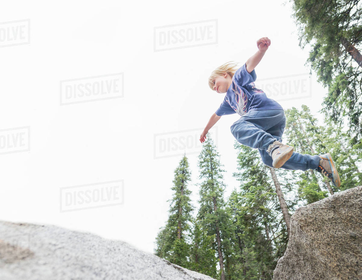 Young boy jumping off rock, low angle view, Sequoia National Park ...