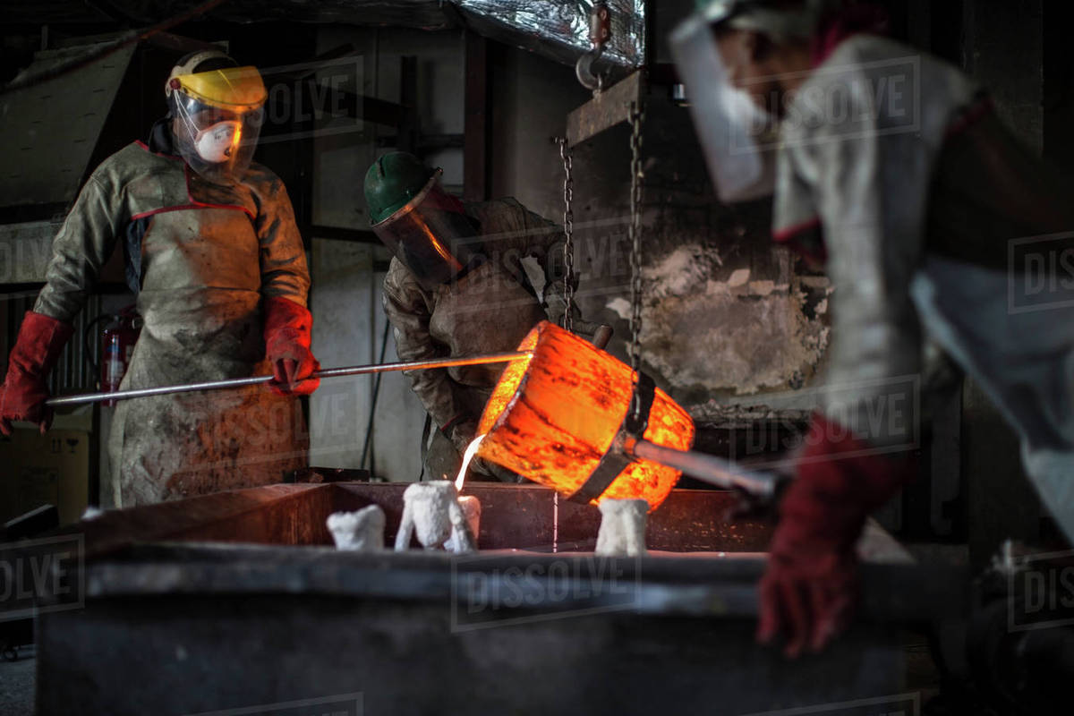 Metalworkers working in foundry, pouring molten bronze - Stock Photo ...