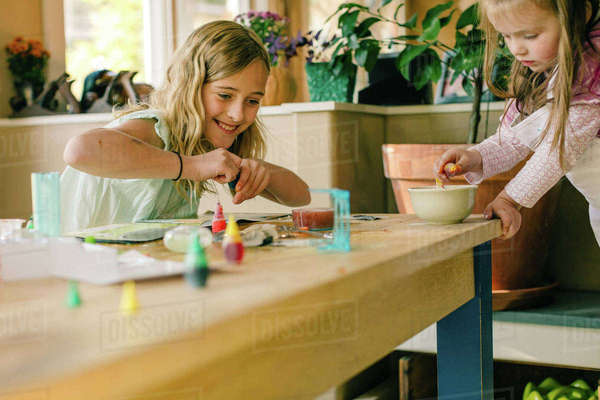 Two girls doing science experiment at table - Stock Photo - Dissolve