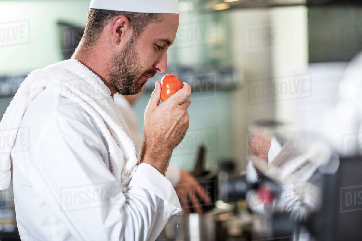 Chef smelling tomato - Stock Photo - Dissolve