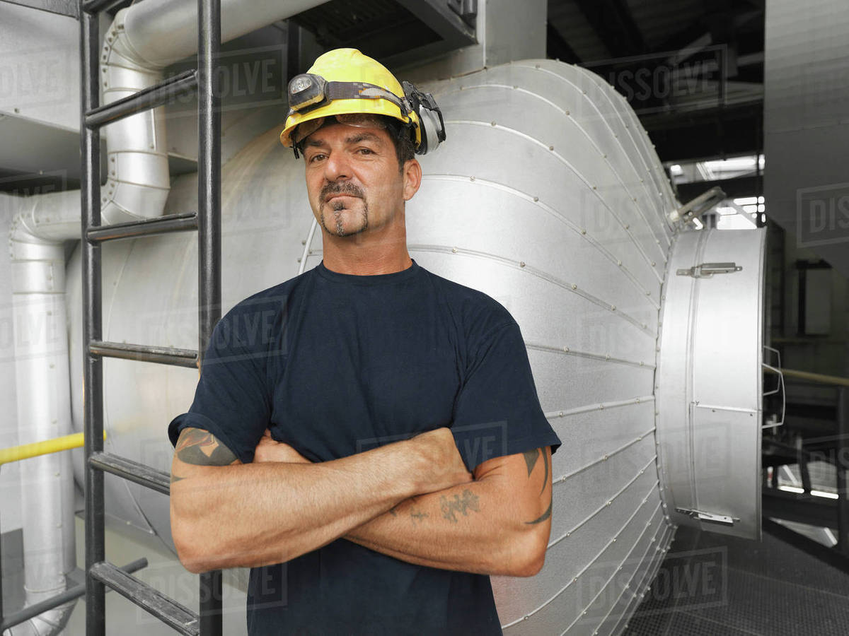 Worker in hard hat standing in factory - Stock Photo - Dissolve