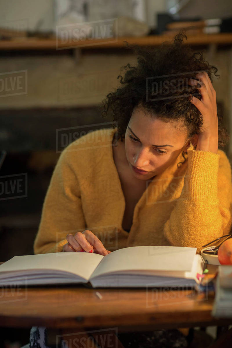 Woman reading book at desk - Stock Photo - Dissolve