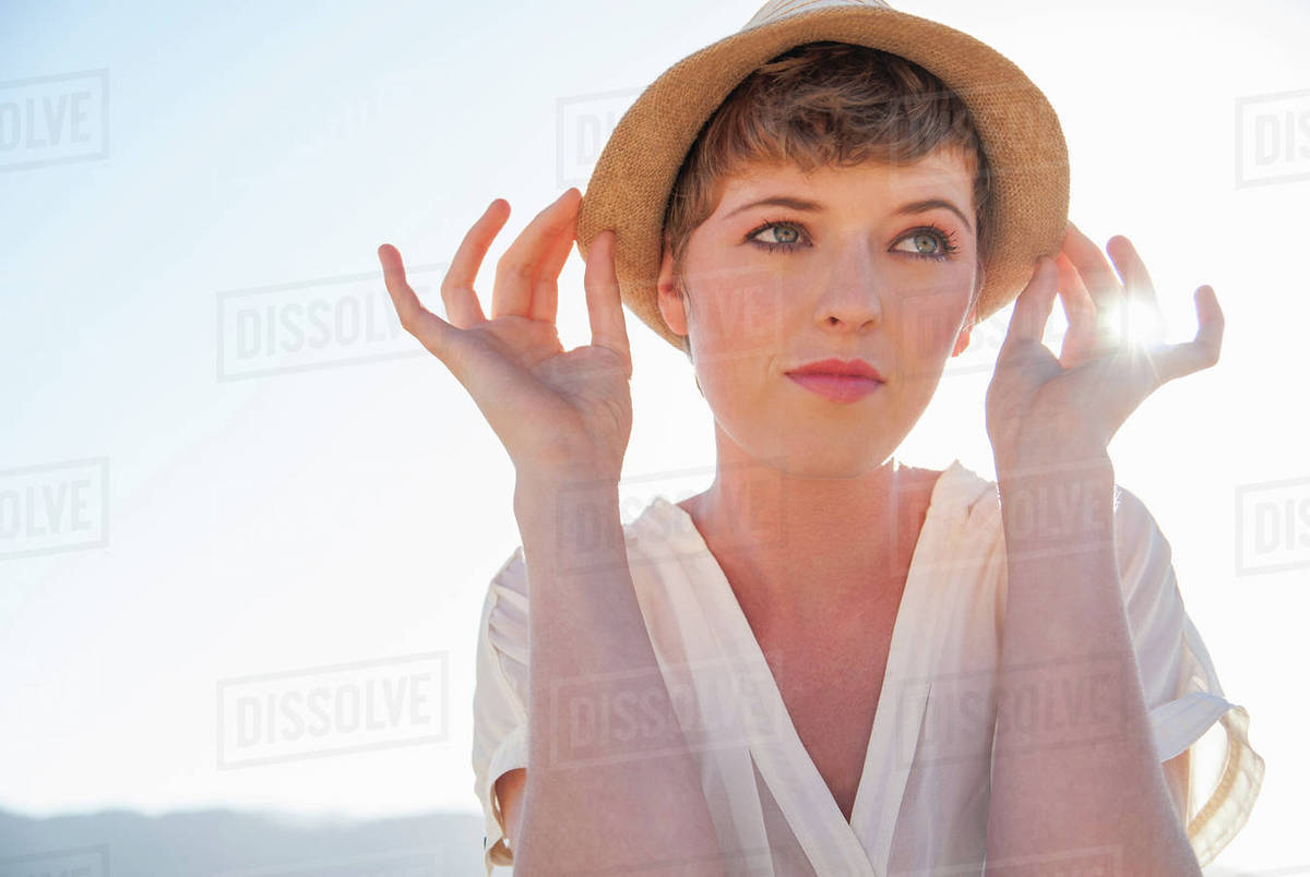 Woman holding her hat down by its rim - Royalty-free Stock Photo | Dissolve