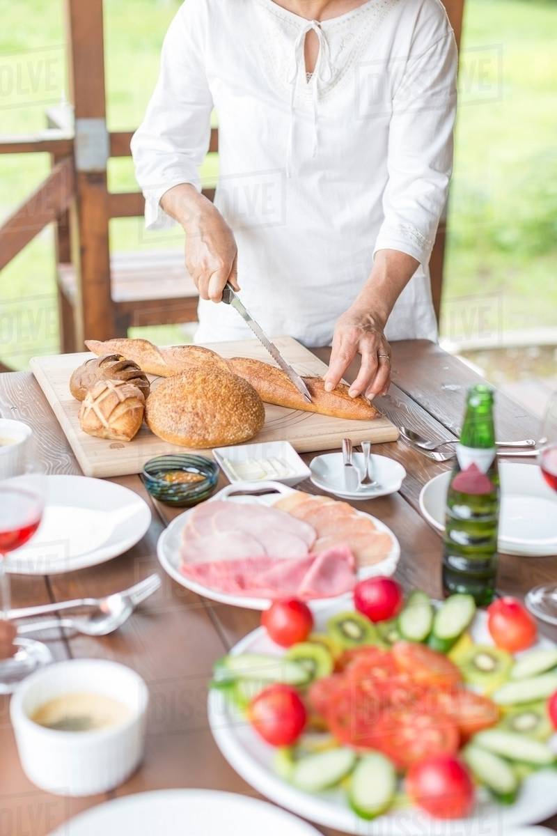 Woman cutting baguette - Royalty-free Stock Photo | Dissolve