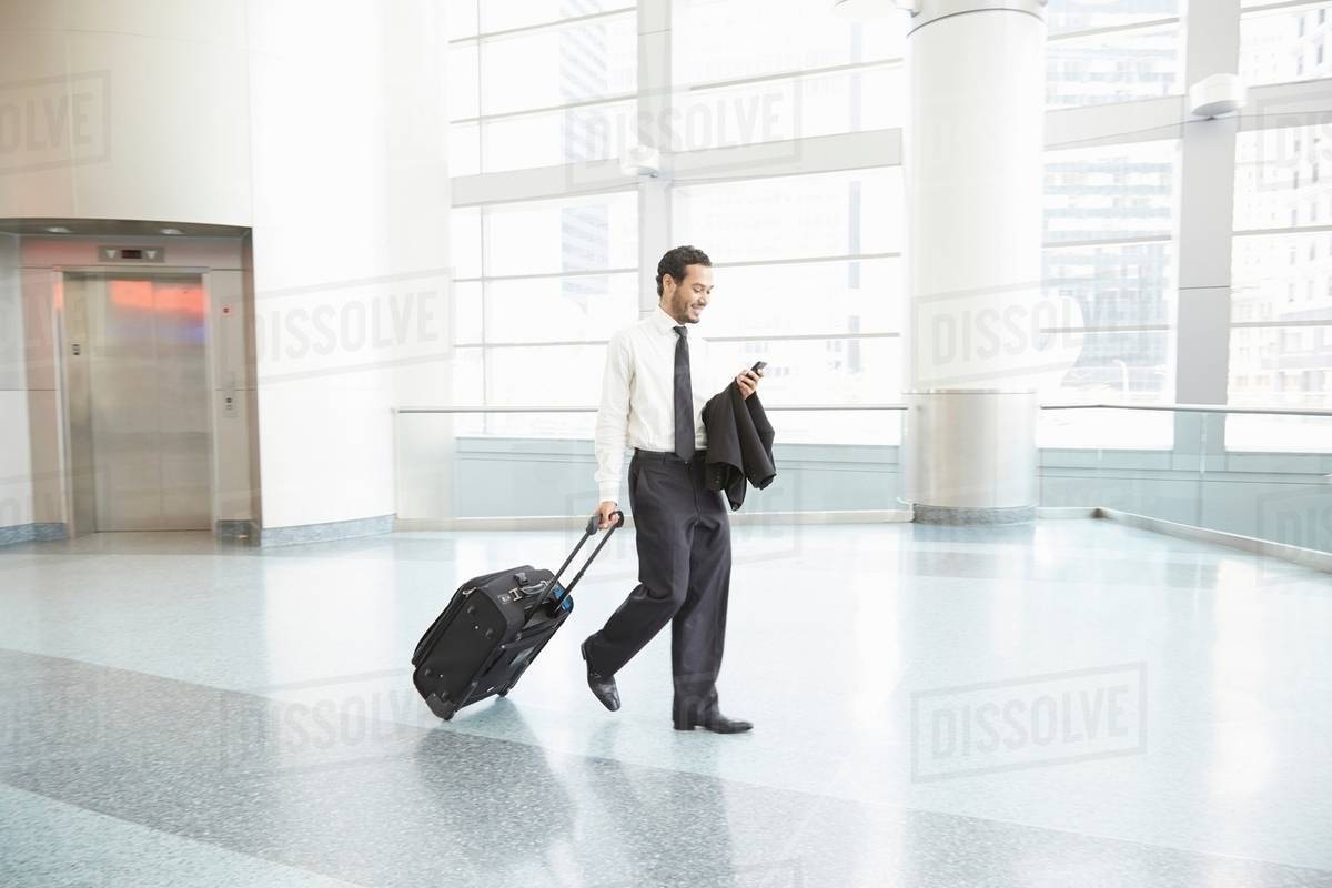 Businessman pulling wheeled suitcase - Royalty-free Stock Photo | Dissolve