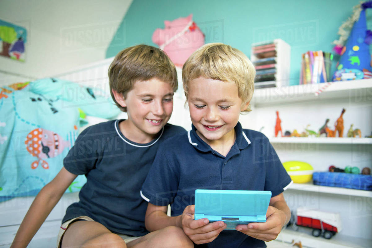Brothers with handheld computer game - Stock Photo - Dissolve