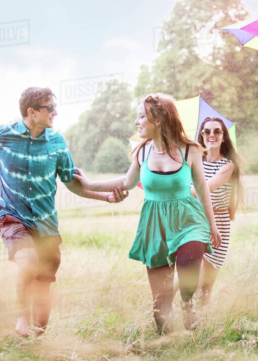 Friends walking in field smiling - Royalty-free Stock Photo | Dissolve