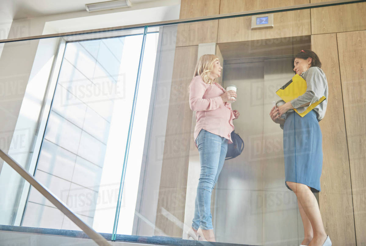 Colleagues in office building waiting for lift - Stock Photo - Dissolve