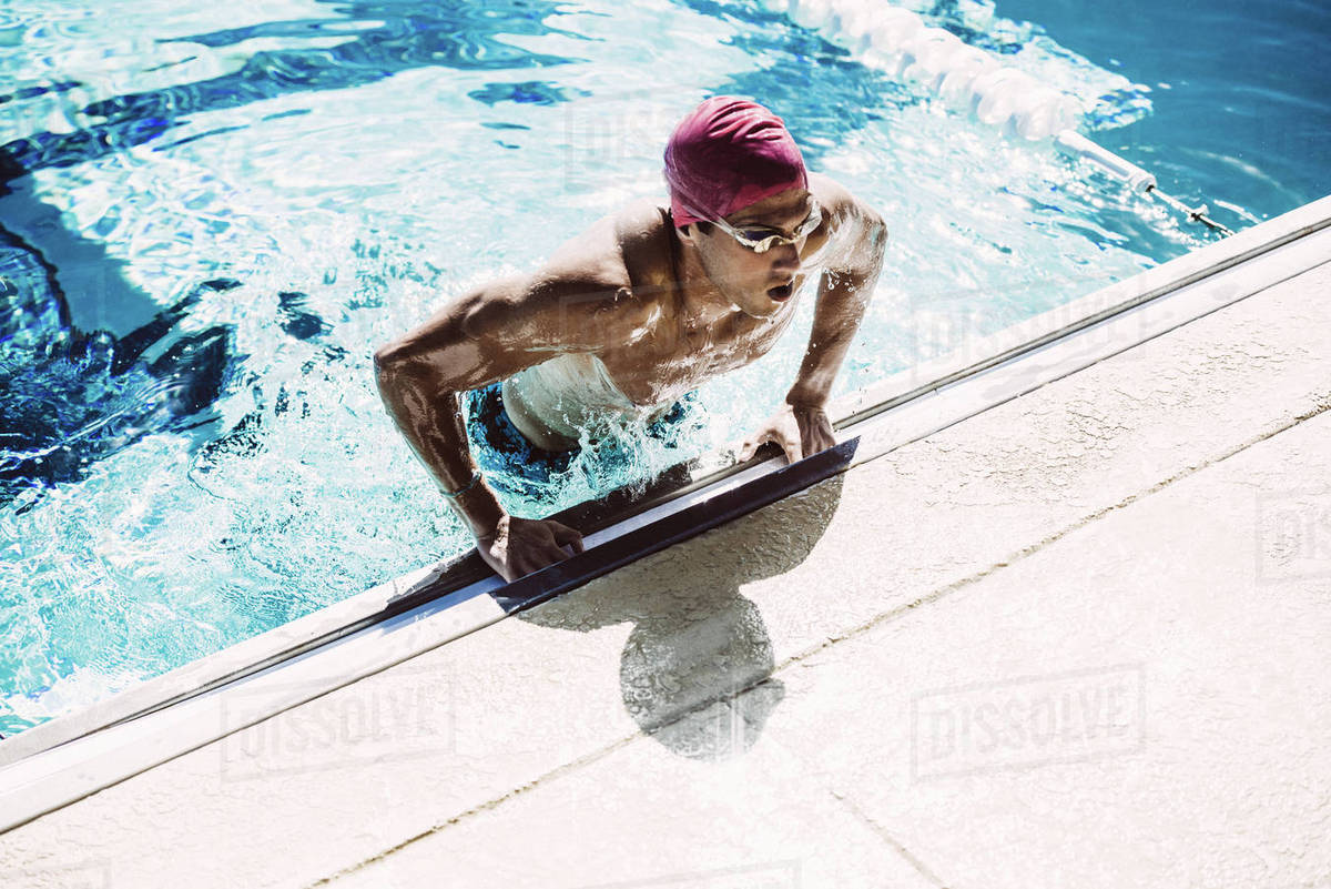 Swimmer climbing out of pool - Stock Photo - Dissolve