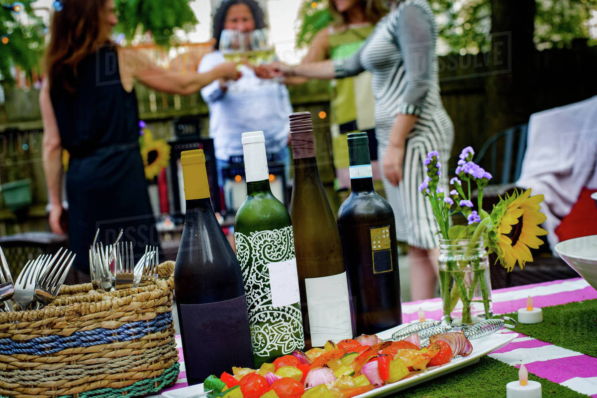 Group of women at garden party, holding wine glasses, making toast ...