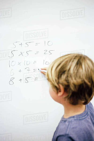 Young boy doing sums on whiteboard, rear view - Stock Photo - Dissolve