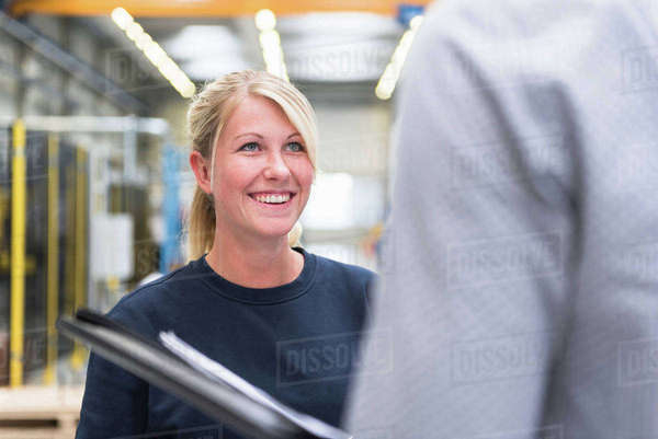 Factory worker smiling at colleague - Stock Photo - Dissolve