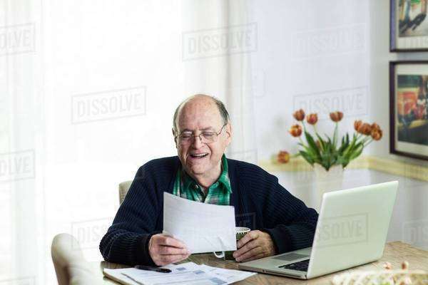 Senior man looking at documents on desk at home - Royalty-free Stock ...