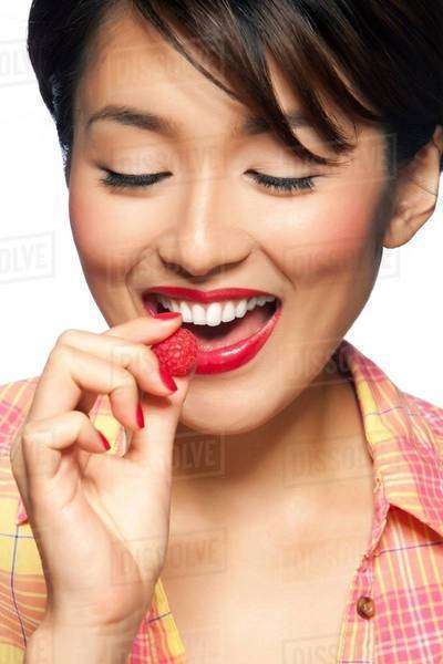 Young woman eating raspberry, studio shot - Royalty-free Stock Photo ...