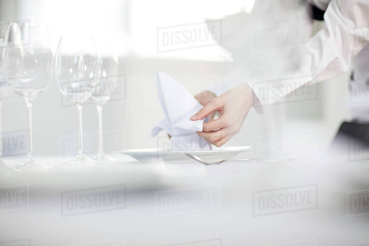 Waitress laying table in restaurant, mid section - Stock Photo - Dissolve