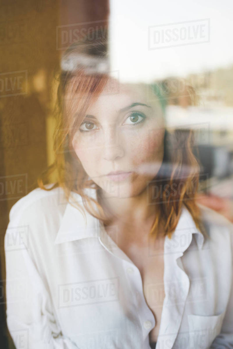 Portrait of beautiful young woman looking through window - Stock Photo ...