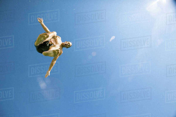 Young man jumping, mid air, low angle view - Stock Photo - Dissolve